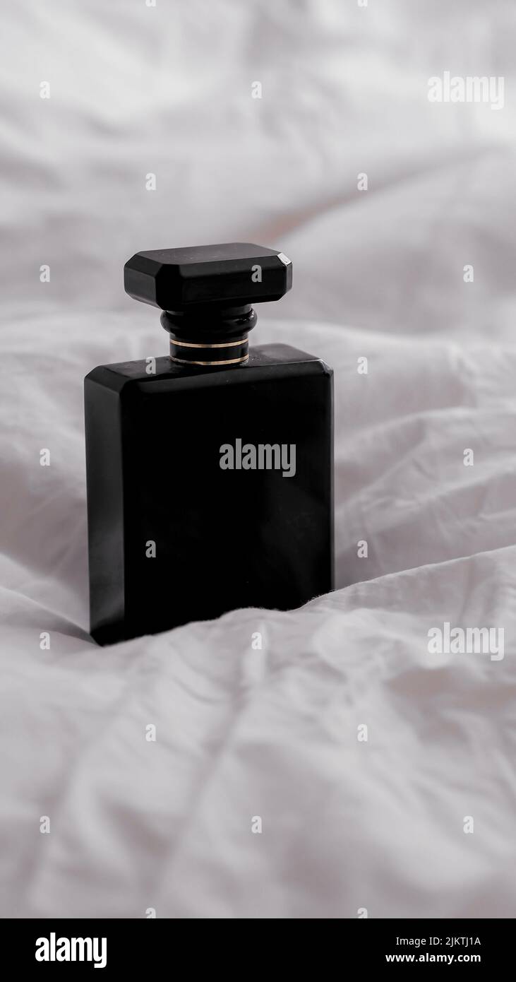 A vertical closeup of a black rectangular perfume bottle on a white ...
