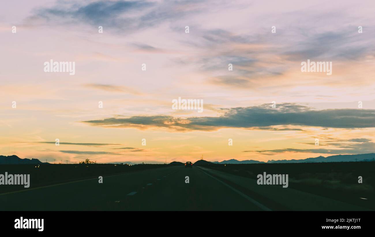 Interstate roadtrip during sunset with cars in the silhouette distan ...