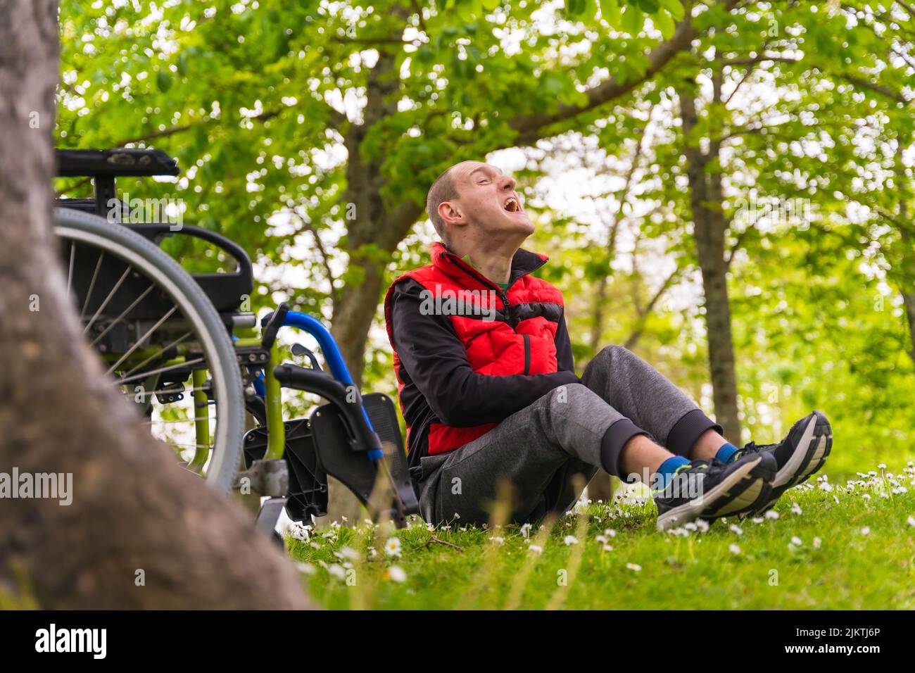 Portrait of a paralyzed young man sitting on the grass next to a ...