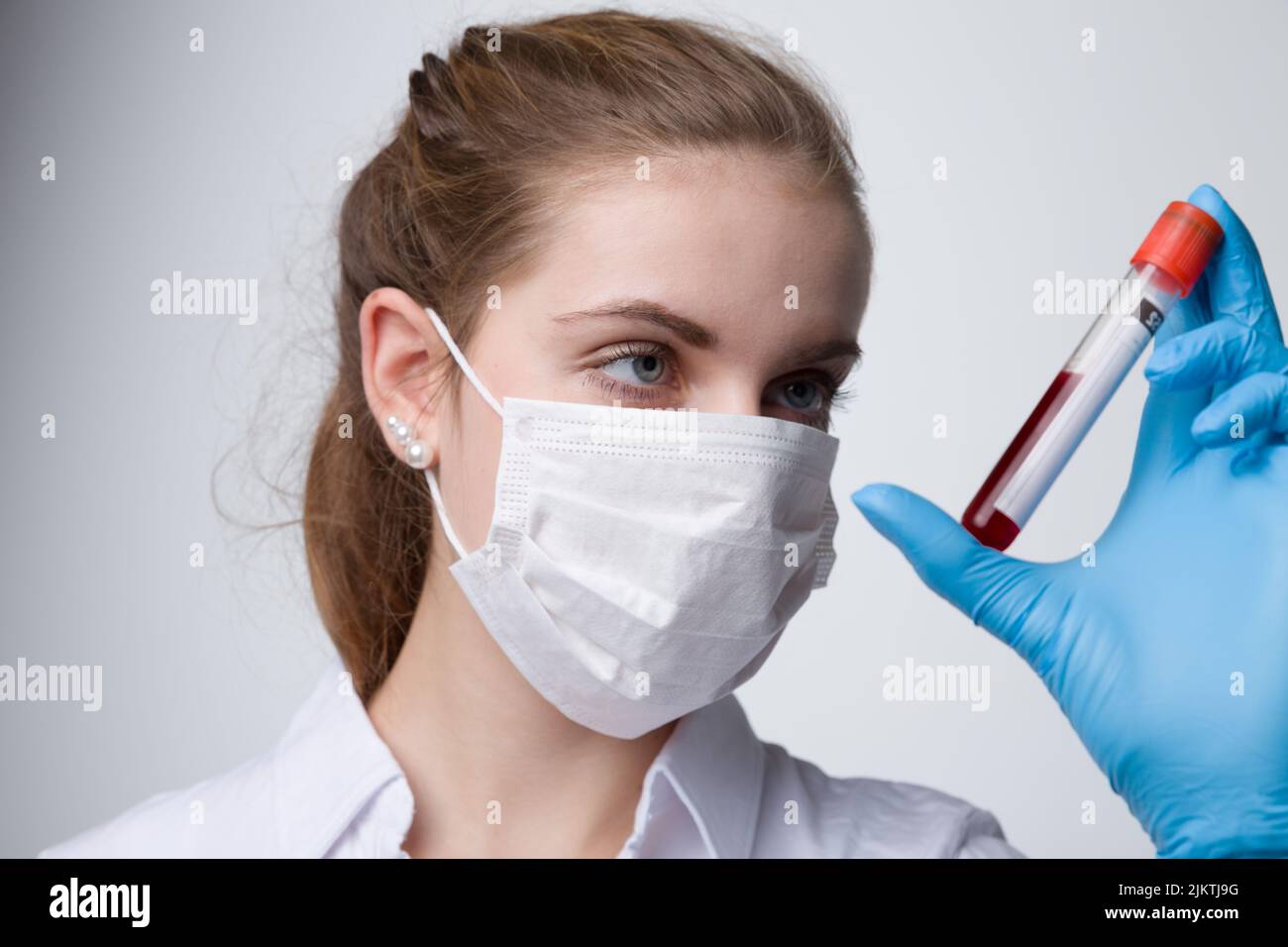 a young nurse with medical face mask and medical gloves is handling a ...