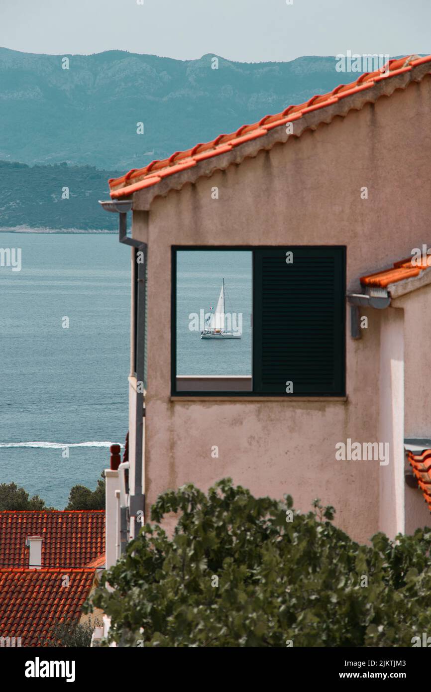 A vertical shot of a boat sailing on the blue sea seen from an open ...