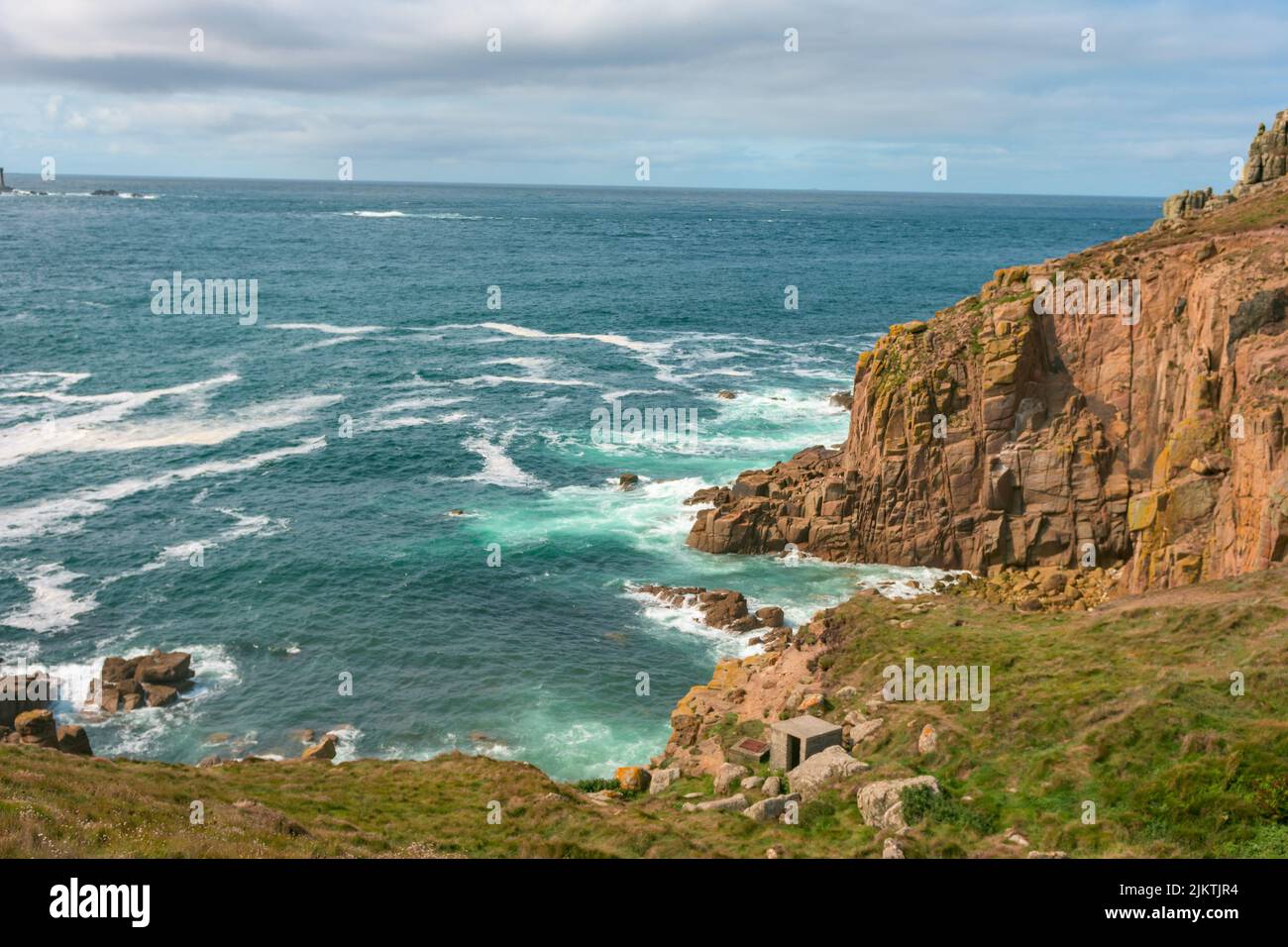 A high angle shot of rugged cliffs on the coast of an ocean with its ...