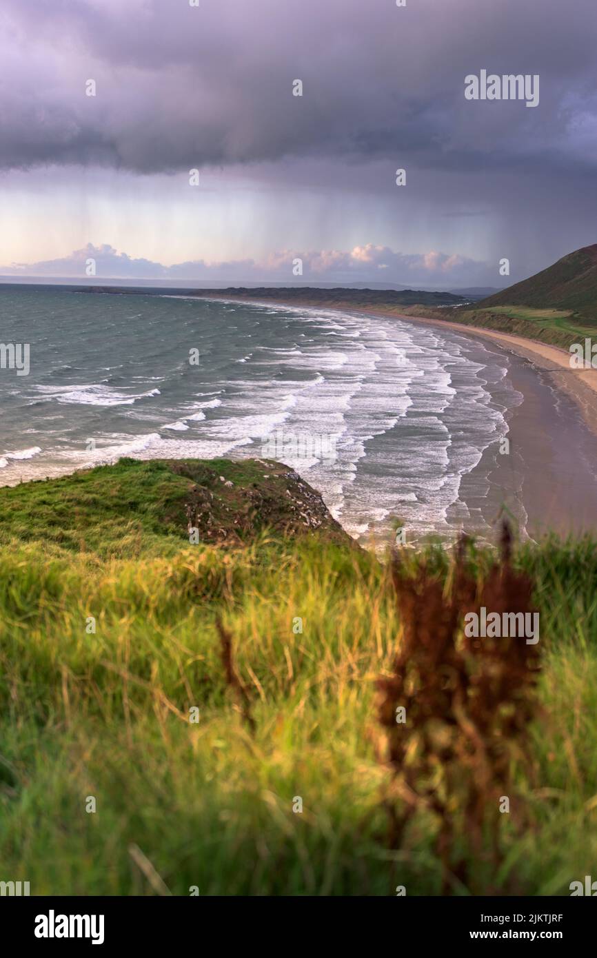 A vertical shot of a sea surrounded by hills under a gloomy sky ...