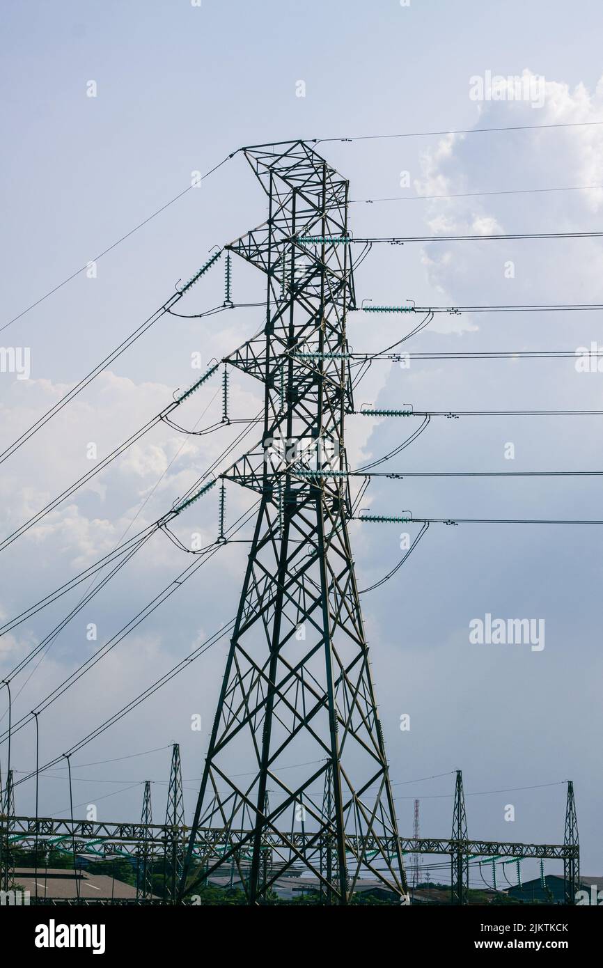 A vertical shot of a power line tower with clouds in the background ...