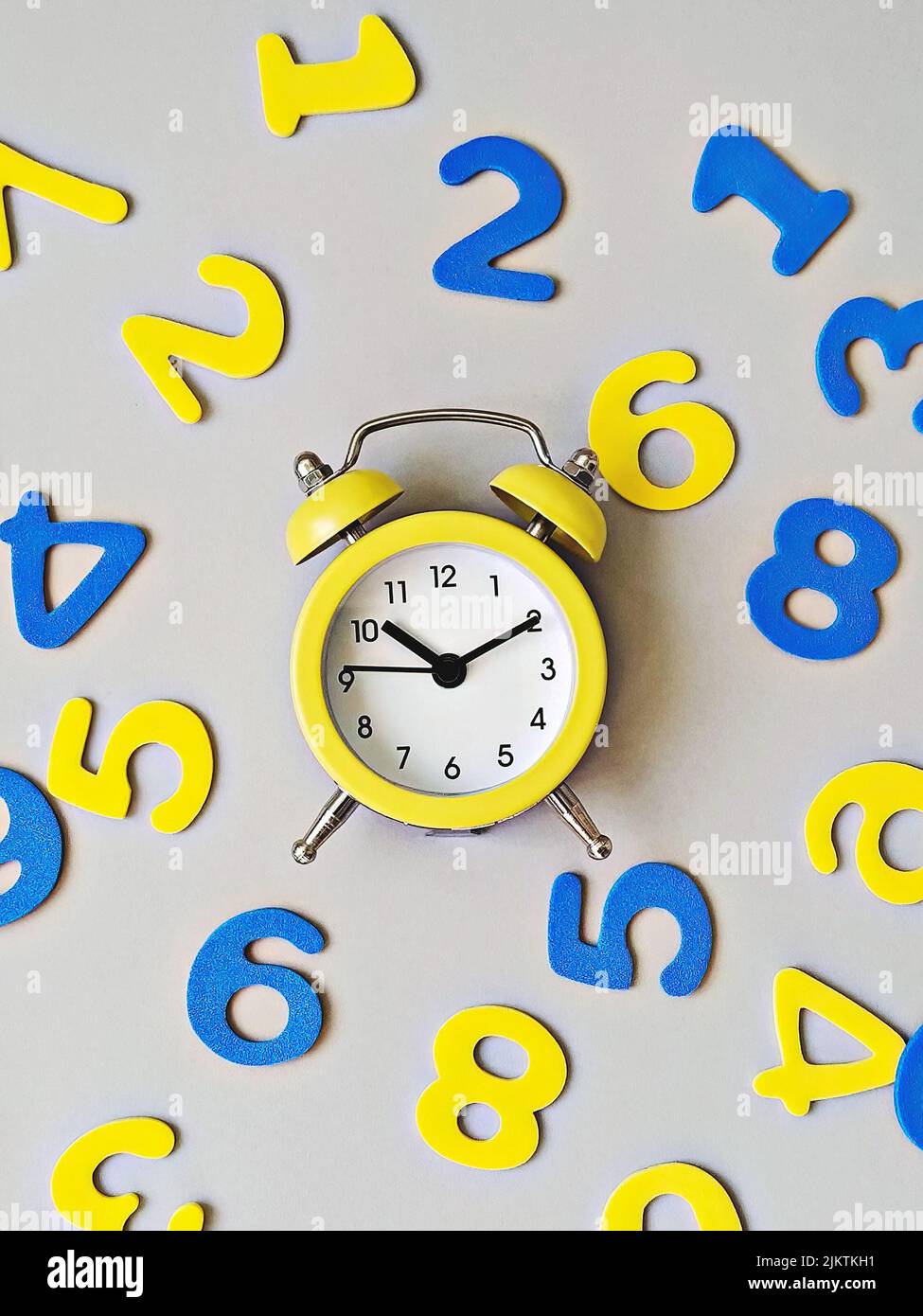 Illuminated yellow alarm clock on ultimate gray background with blue ...