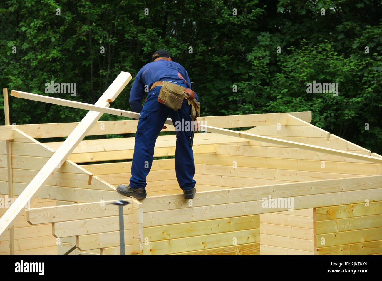 A back shot of a carpenter He builds a house out of wood in daylight in ...