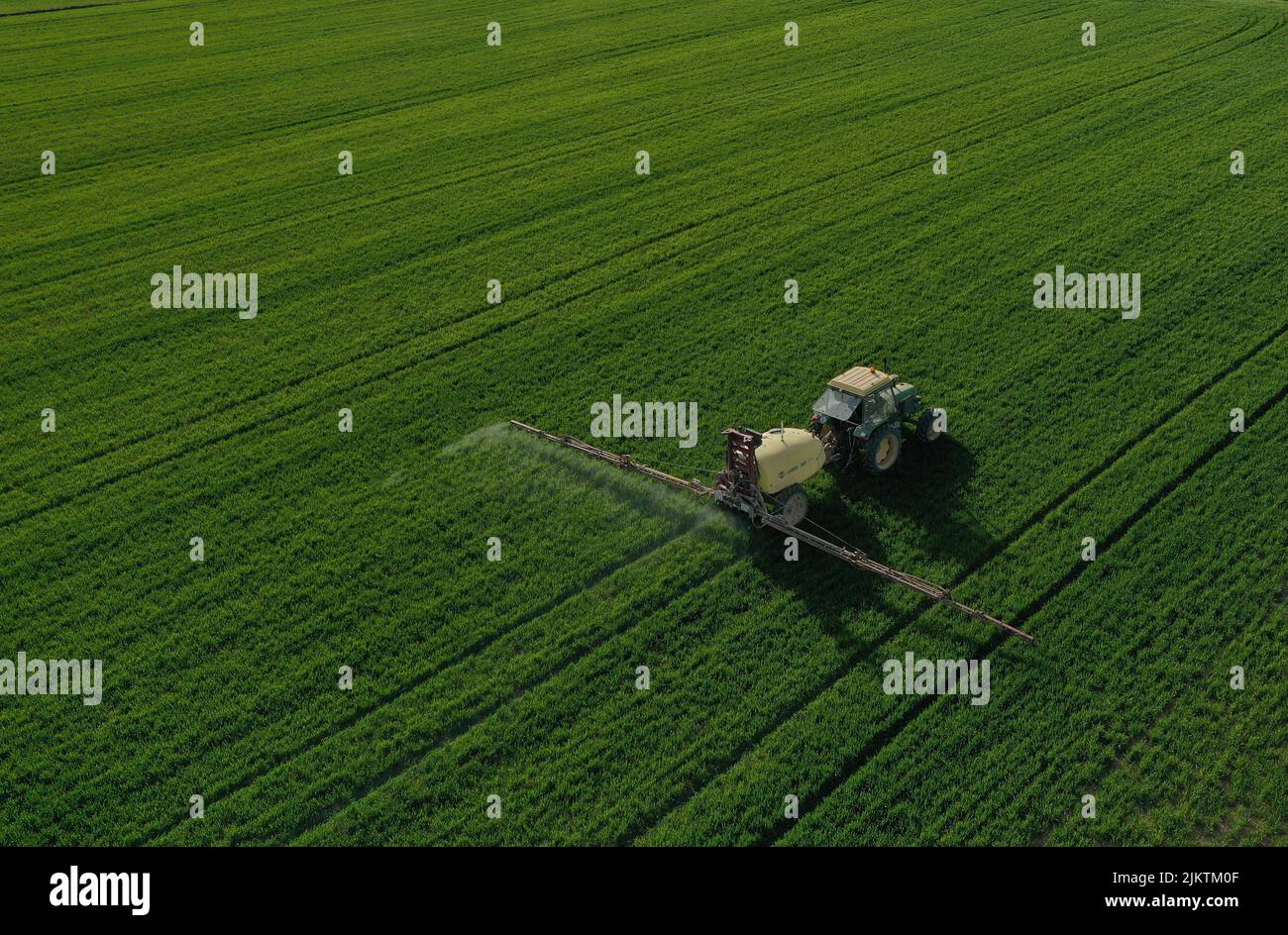 an aerial shot of a tractor fertilizing a green crop field Stock Photo ...