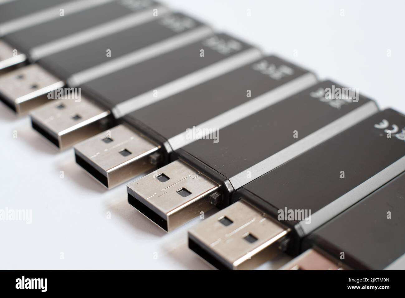 Many black USB sticks in a row with white background. Production of ...