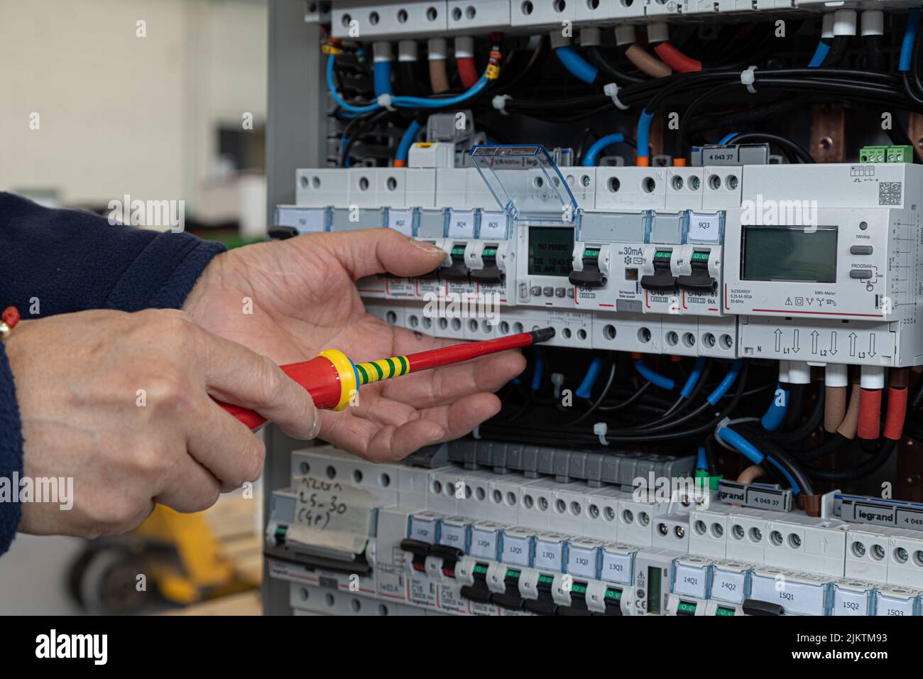 A closeup of the hands holding a screw while working on the electrical ...