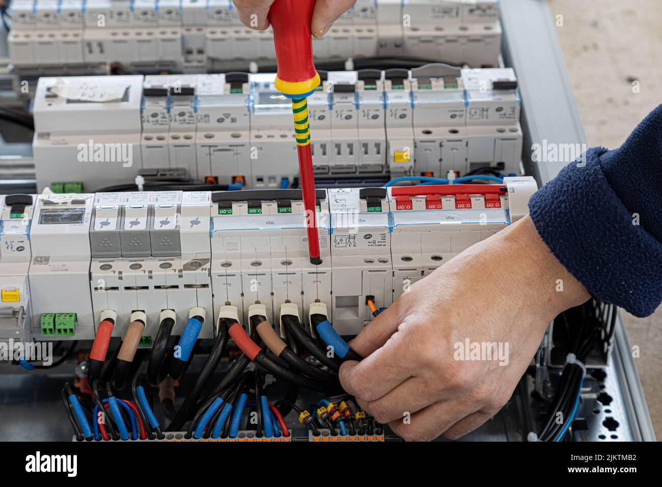 A closeup of the hands holding a screw while working on the electrical ...