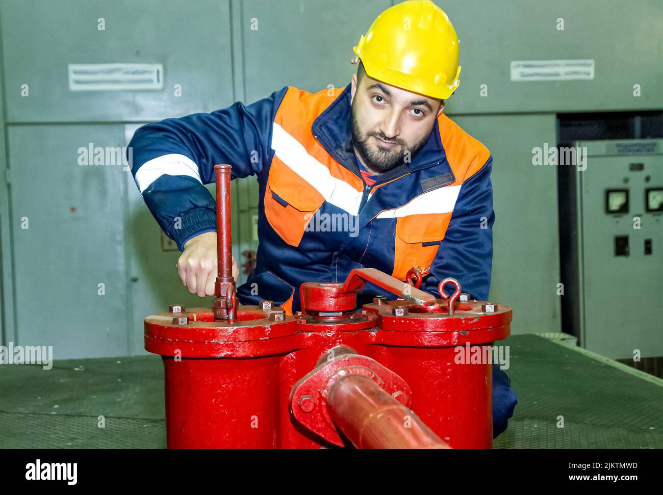 A Caucasian man working on an equipment in his uniform and helmet Stock ...