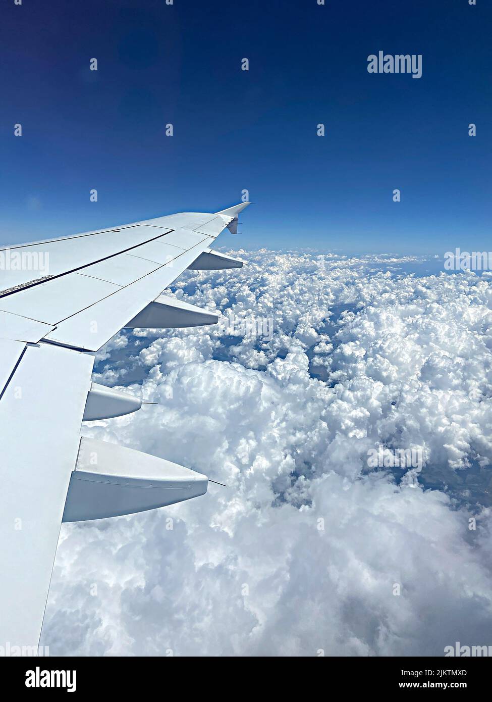 A vertical aerial of white fluffy clouds in the blue sky seen from an ...