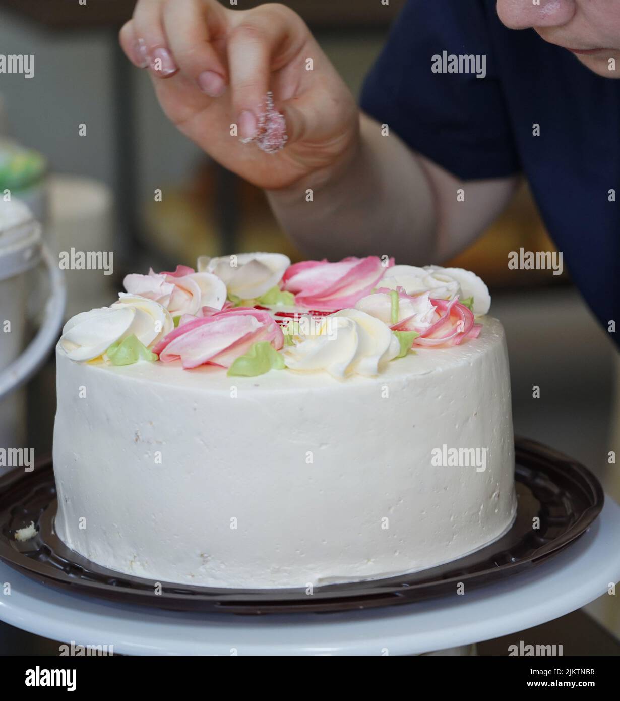 A vertical shot of a freshly baked cake with rose decorations on a ...