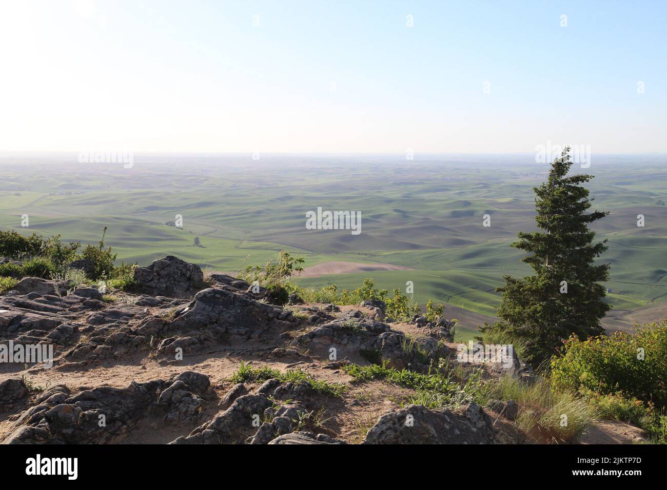 The view of the beautiful land with wavy fields against the blue sky ...