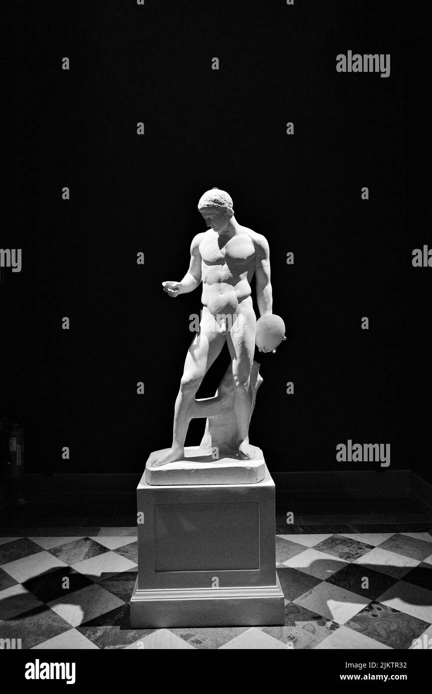 A vertical shot of the Discophoros sculpture on a black background ...