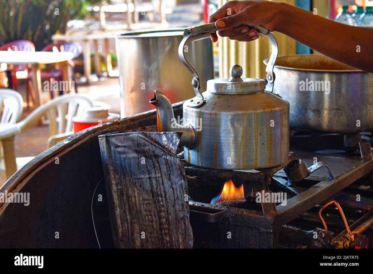 Stock photo of Indian street tea stall, a man holding tea kettle and ...