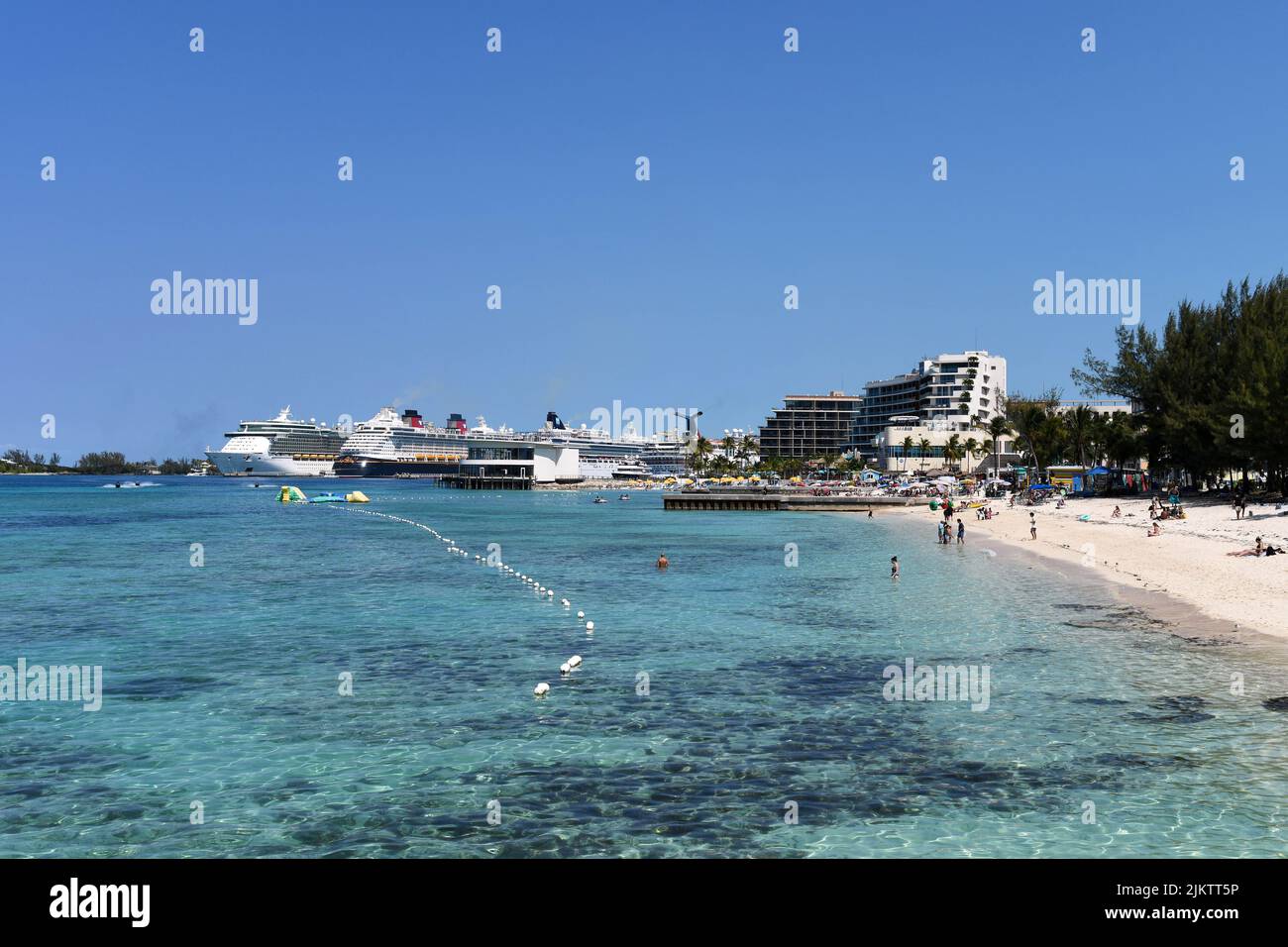 A crystal clear sea and sandy beach with cruise ships and resorts in ...