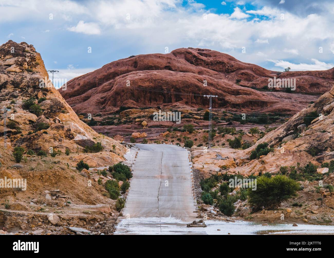 A landscape with a country road passing by arid mountains and hills ...
