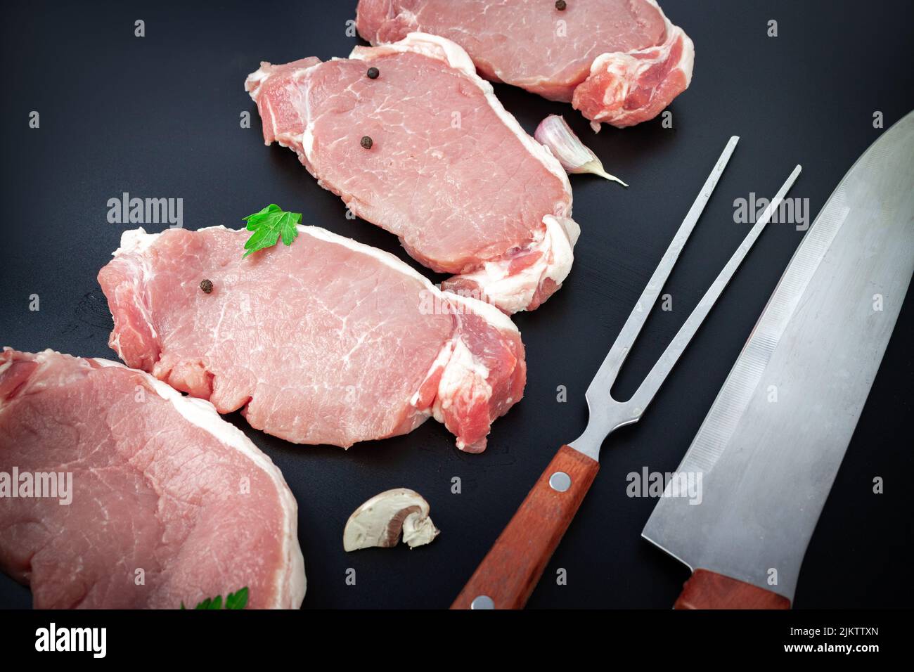 Pieces of raw roast beef meat for grilling on dark background with ...
