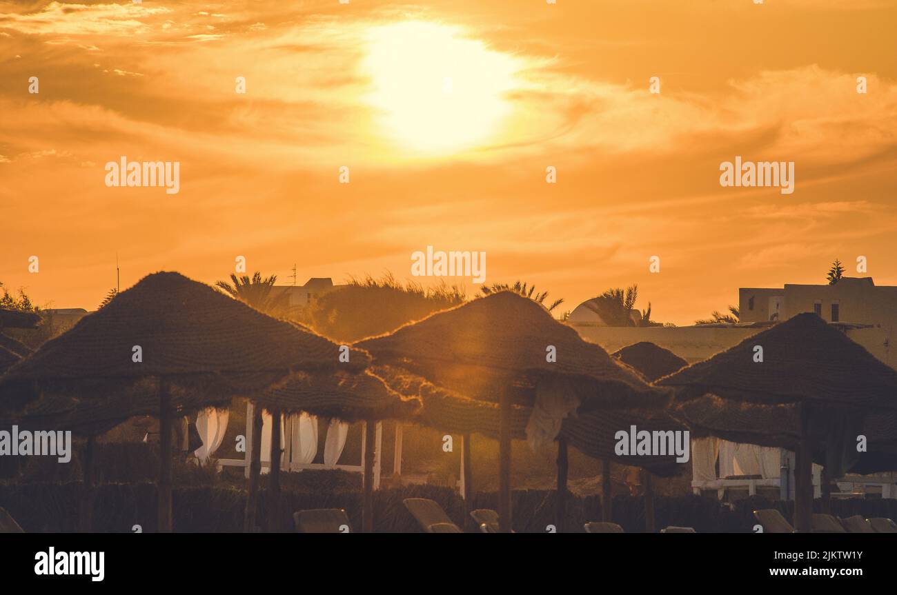 The mesmerizing sunset sky over the coast with thatch umbrellas in ...