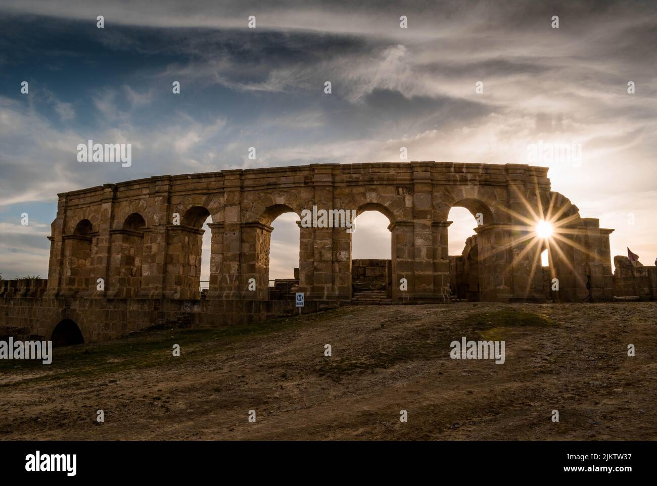 Ancient ruins with a row of connected arches against the cloudy sky ...