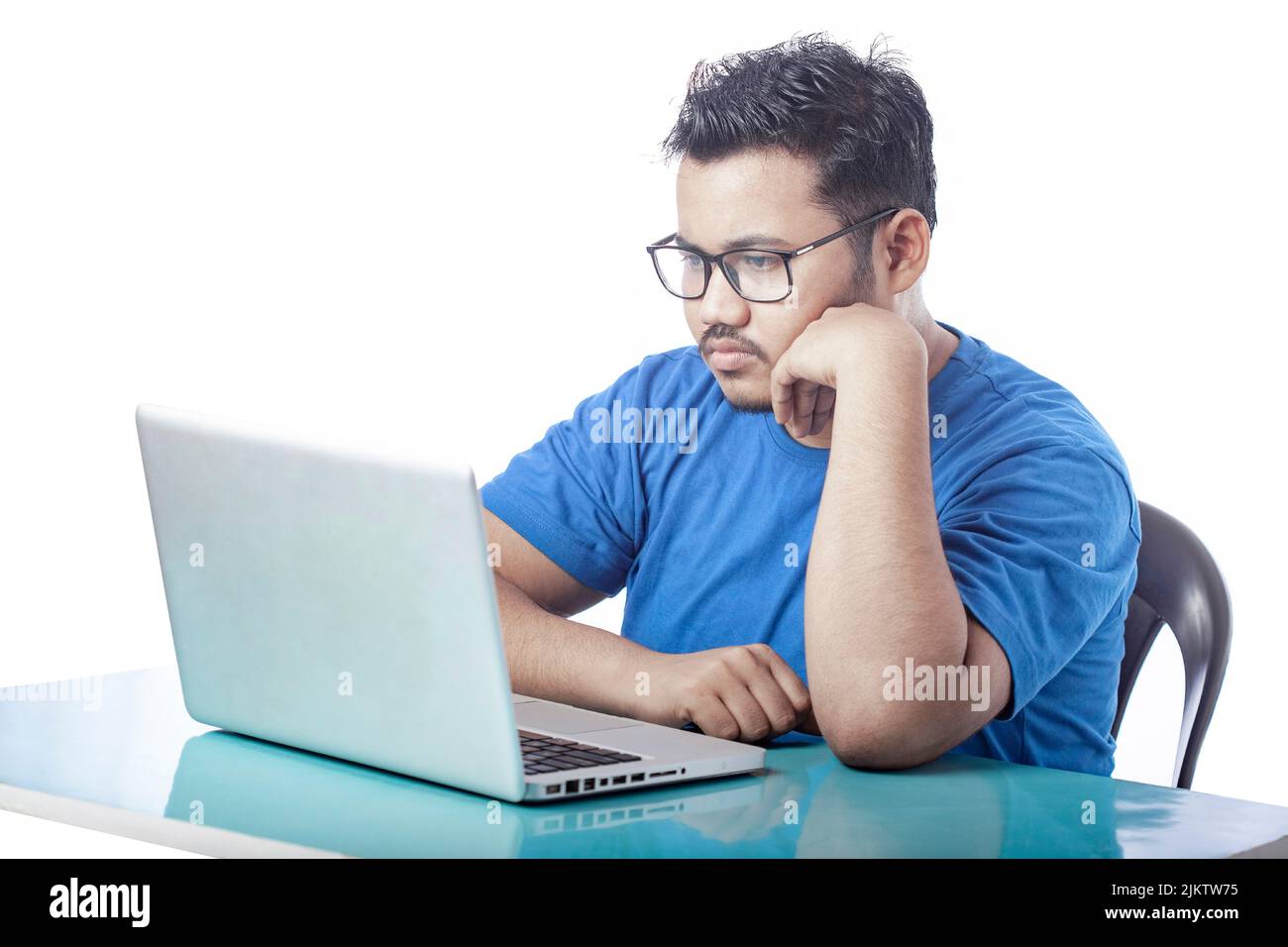 young handsome fat boy sitting in front of a laptop with sad expression ...