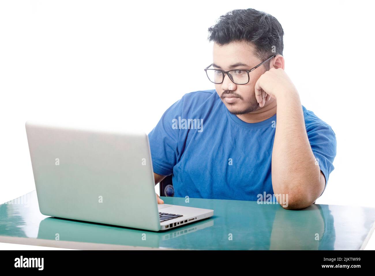 Studio shot of a handsome young boy sitting and using a laptop and ...