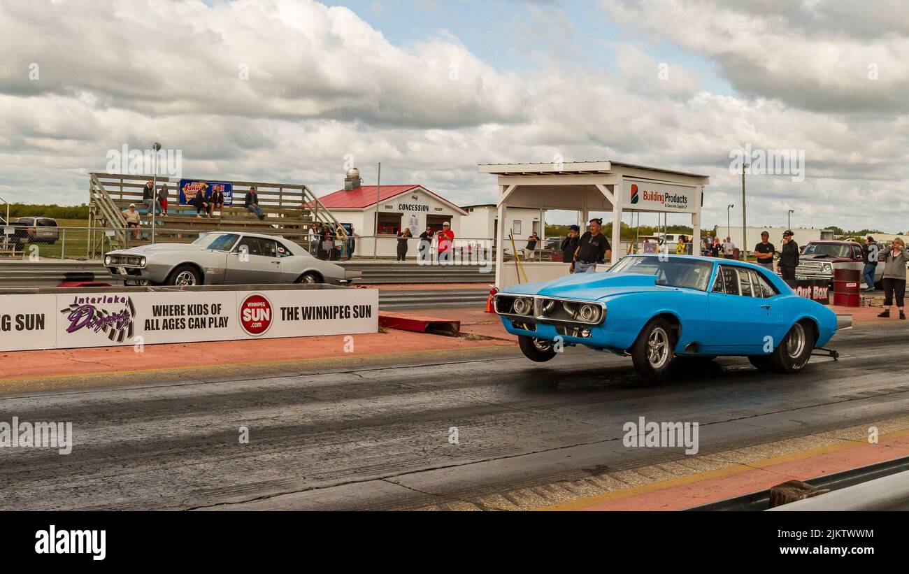 2 cars launching with wheels in the air at the start of a drag race ...