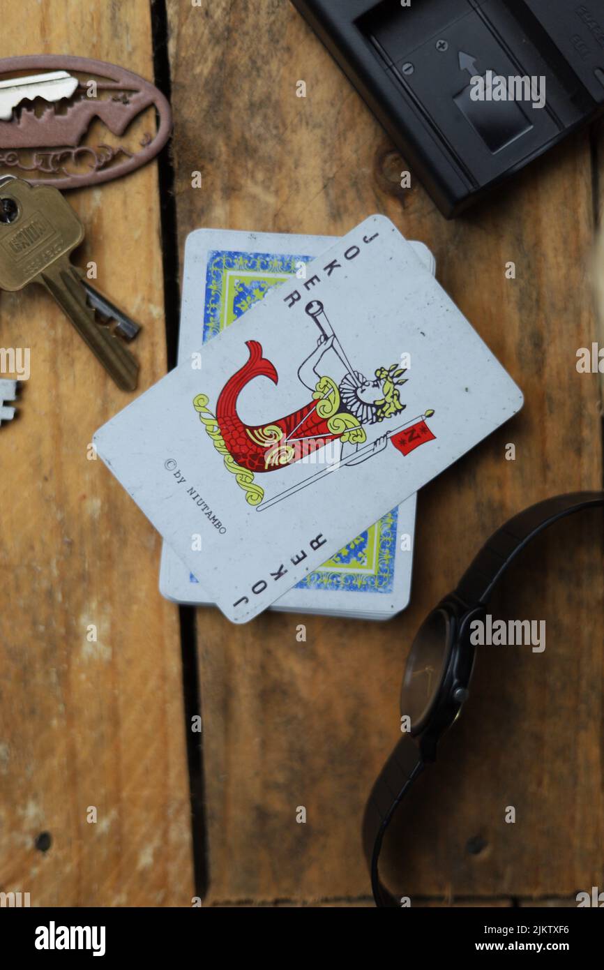 A top view of Joker and a deck of cards with keys and a watch on a ...