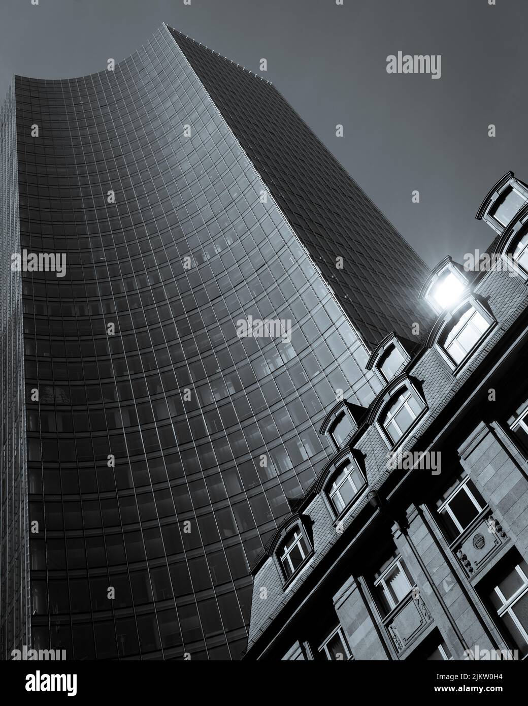 A low angle grayscale view of a tall skyscraper will glass windows with ...