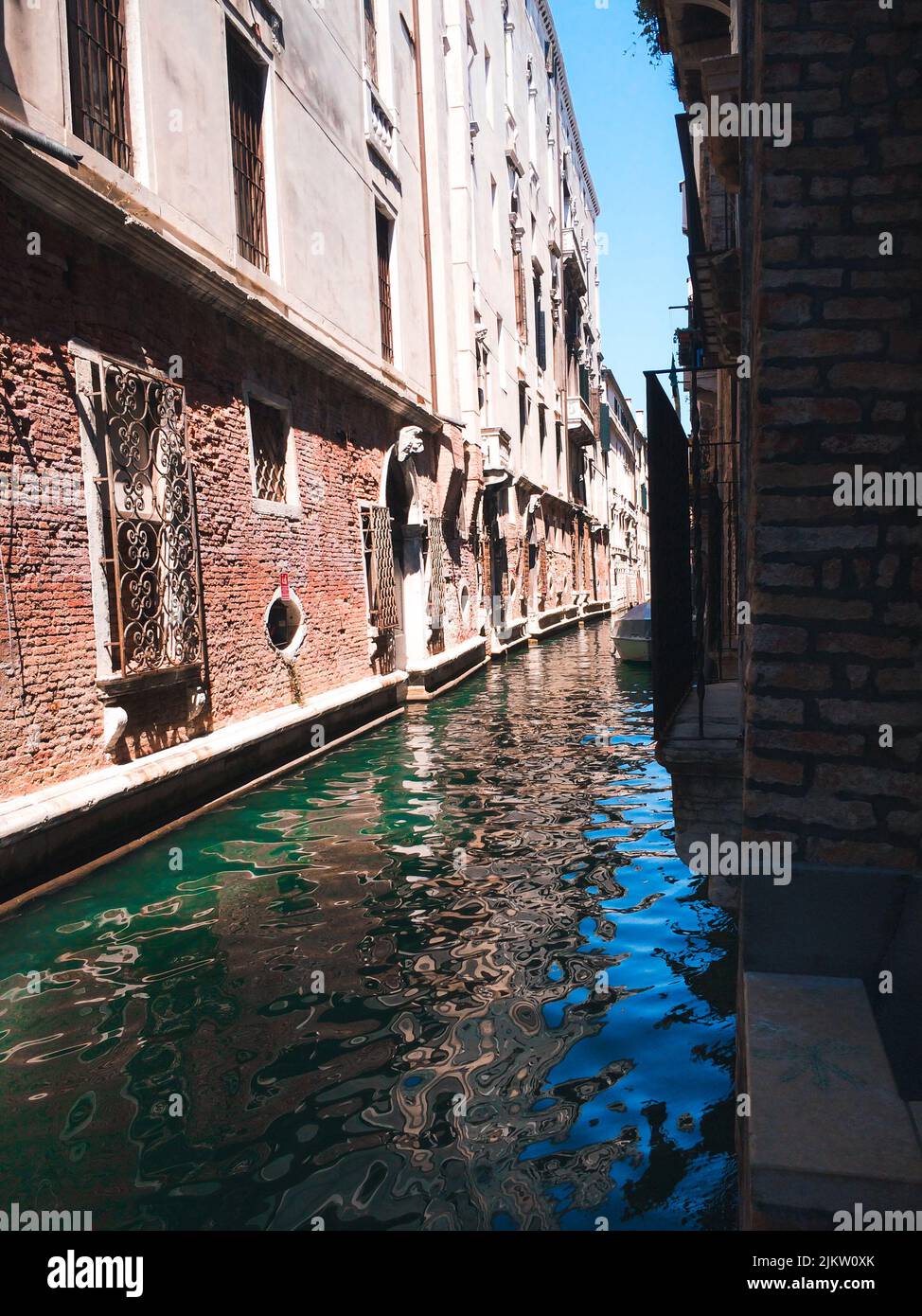A vertical shot of a narrow canal between buildings in Venice, Italy ...