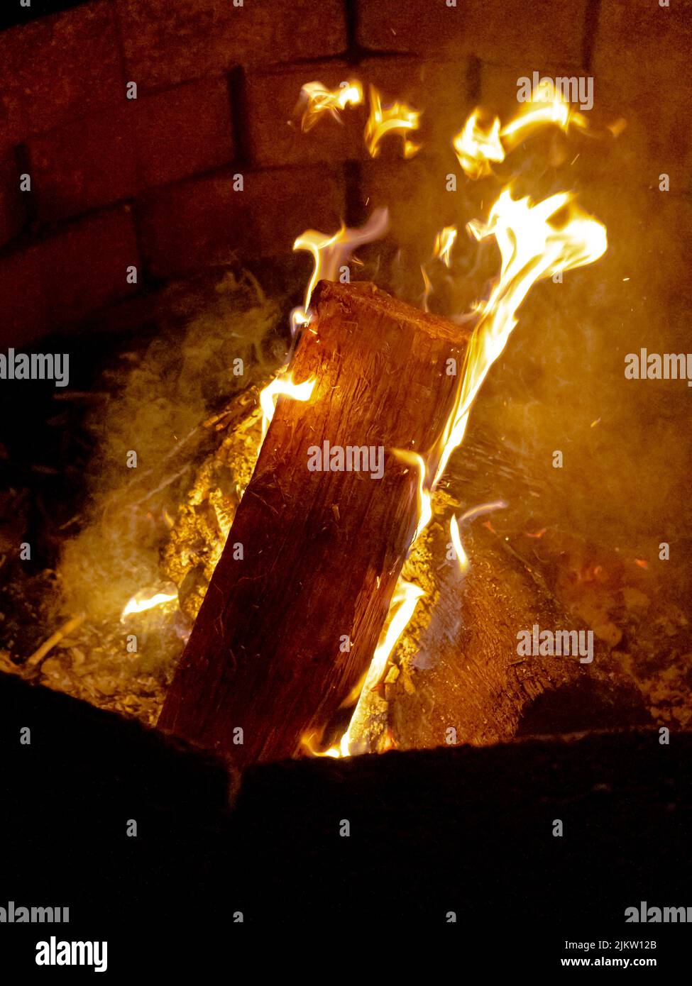 A vertical shot of a burning wooden deck in the ashes in the chimney ...