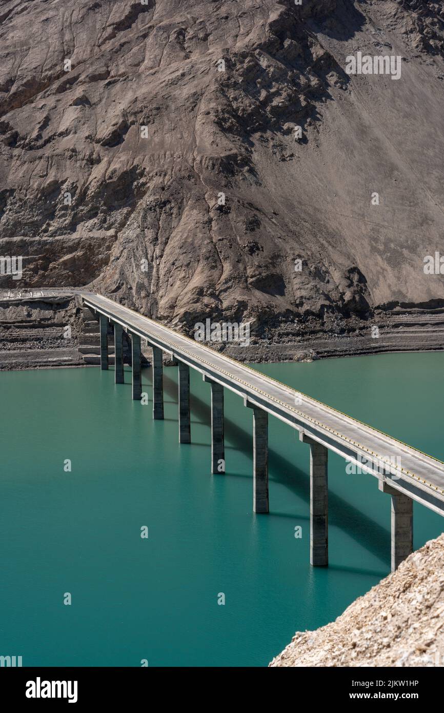A vertical shot of a bridge over the teal water at the bottom of the ...