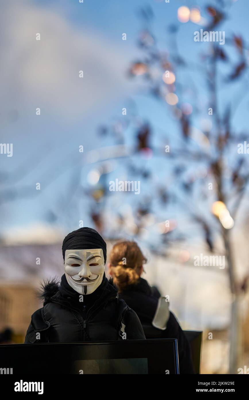 A vertical shot of activists wearing Anonymous masks on the streets of ...