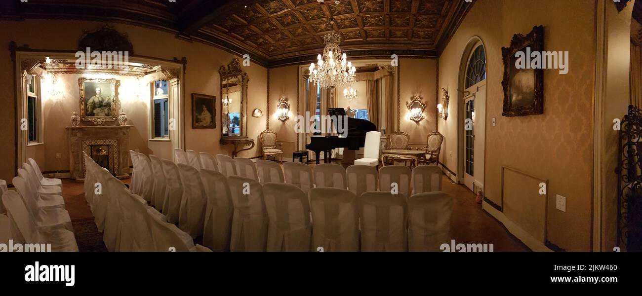 A panoramic shot of a small concert hall with chairs and a grand piano ...