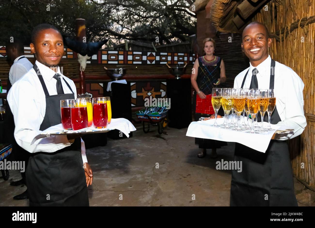 The African waiters holding tray of welcome drinks and smiling at party ...