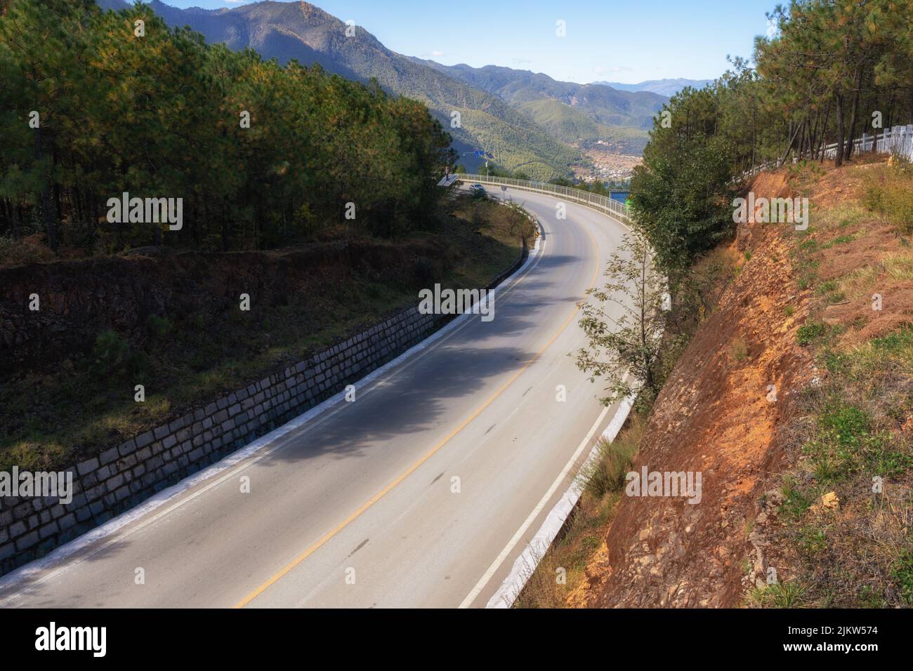 A scenic view of an asphalt road in a rural area surrounded by lush ...