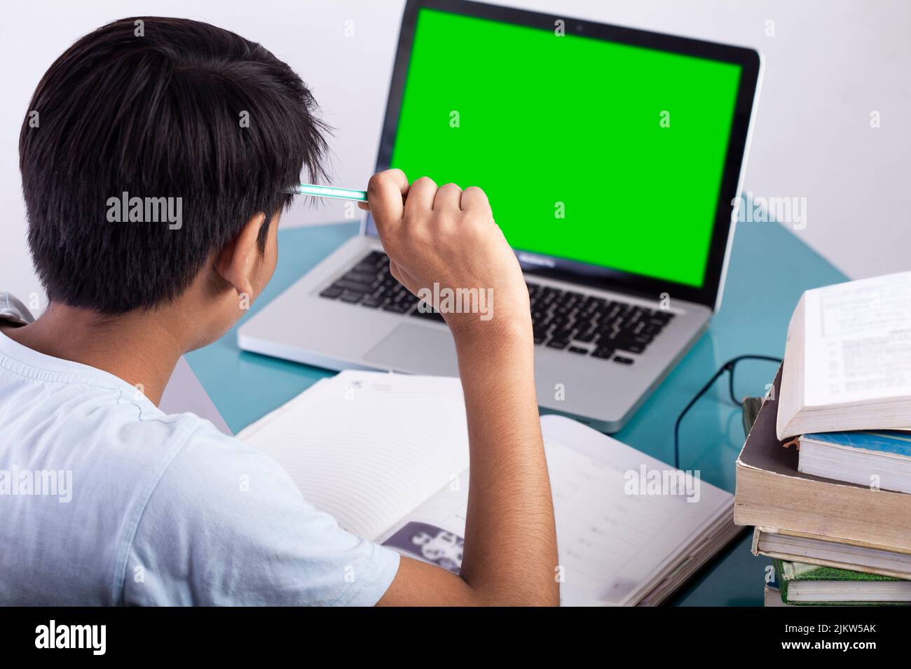 teenage boy looking at laptop green screen and studying online ...