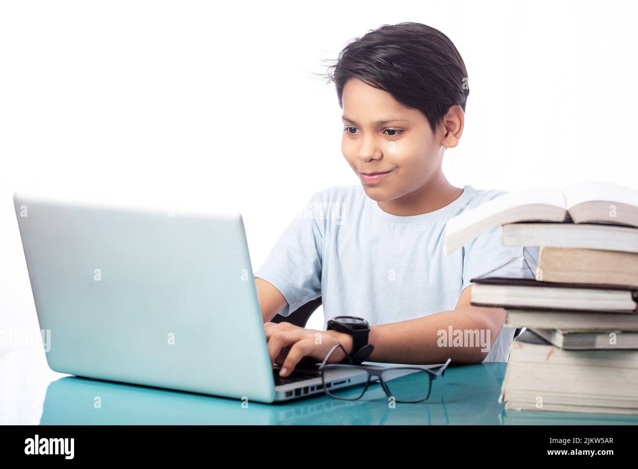 student typing on laptop with some books on desk in white background ...