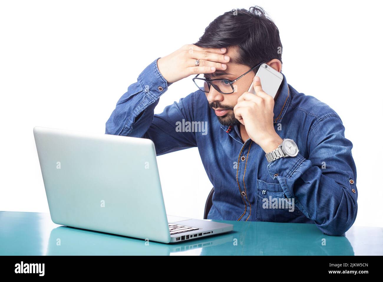 tensed man talking on cell phone and looking sadly at computer screen ...