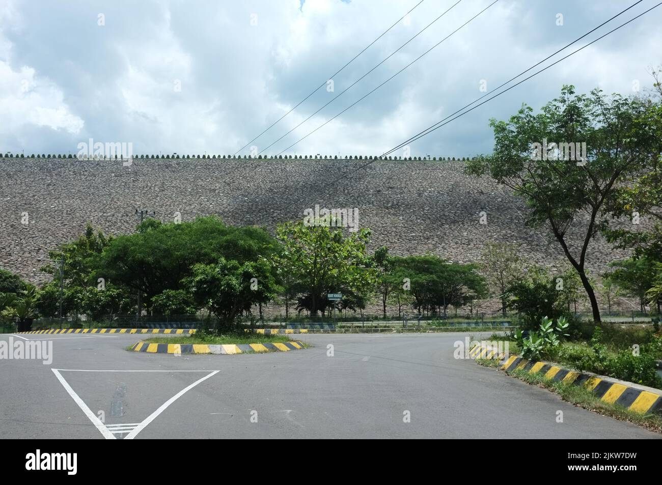 A view of empty traffic roads surrounded by trees under the cloudy sky ...