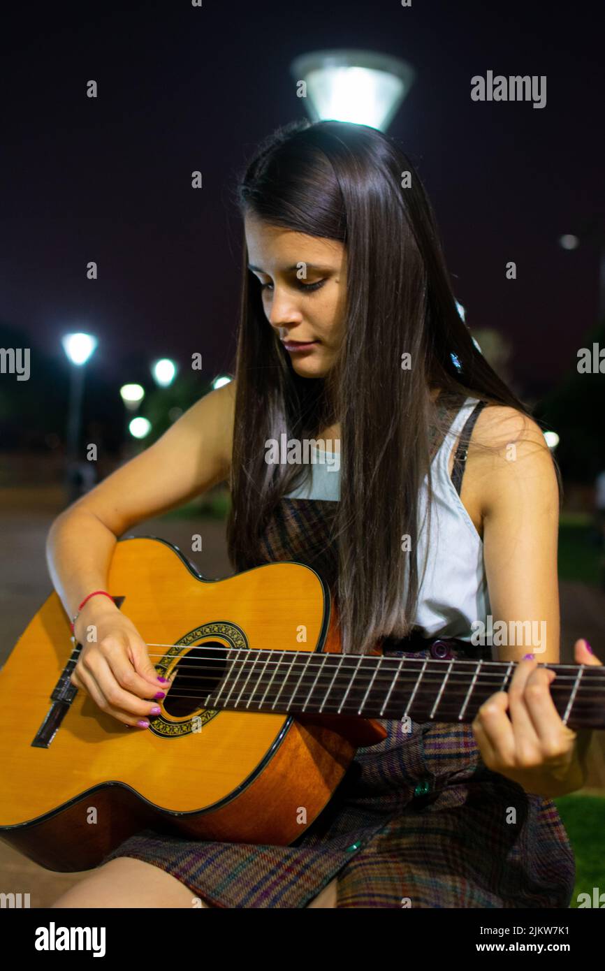 A beautiful female playing guitar in the park at night Stock Photo - Alamy