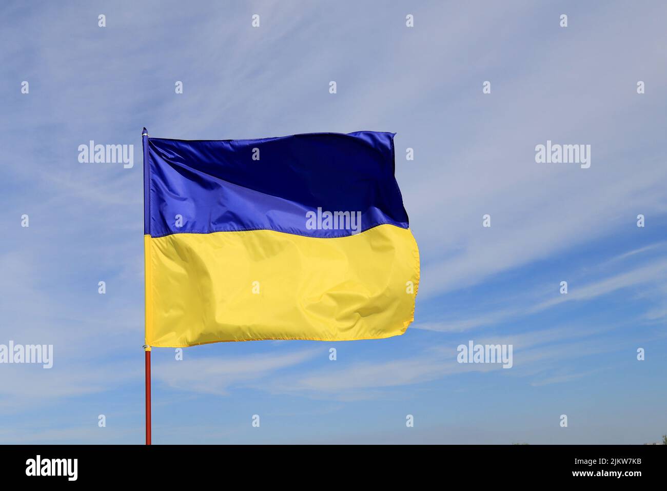 Ukraine flag, national symbol fluttering in cloudy blue sky. Yellow ...