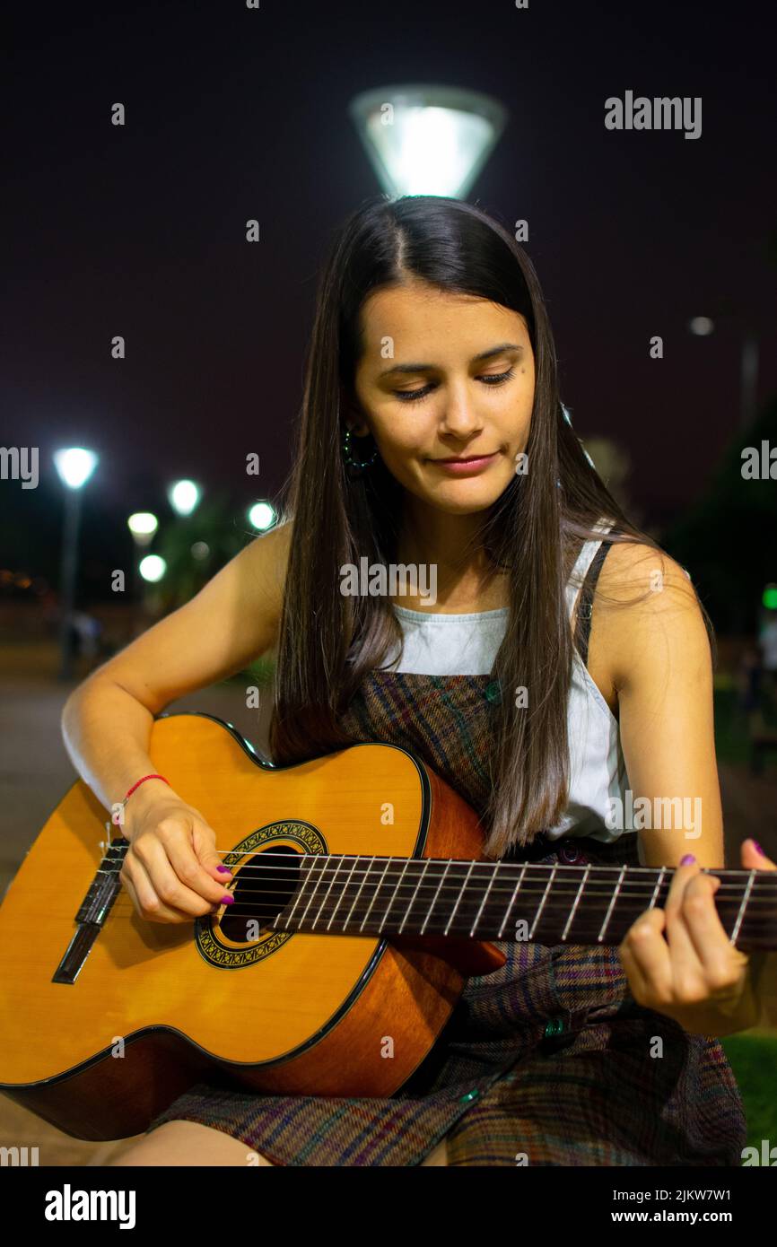 A beautiful female playing guitar in the park at night Stock Photo - Alamy