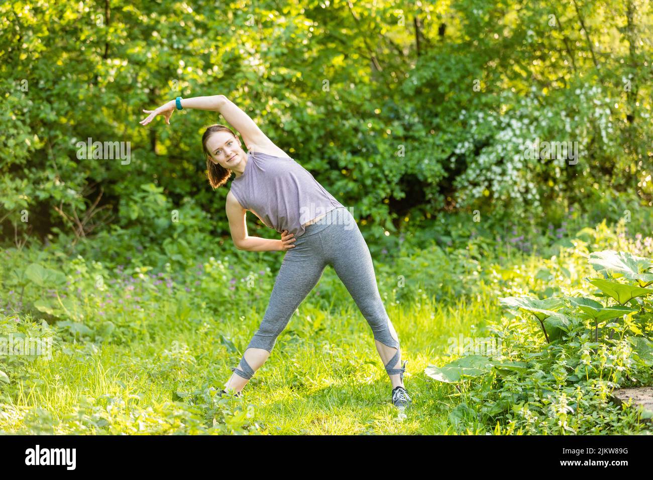 Young woman makes stretching exercises in nature Stock Photo - Alamy
