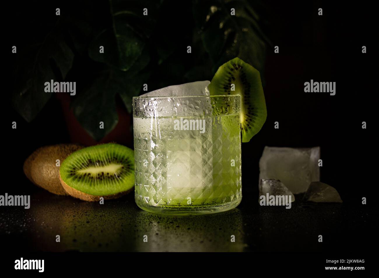 A closeup of a fresh iced kiwi cocktail in a rox glass with dark ...