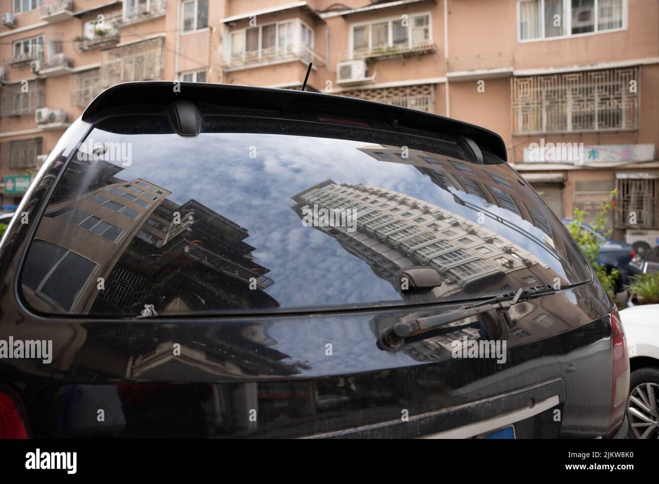 A back view of a black modern car with building reflection in the ...