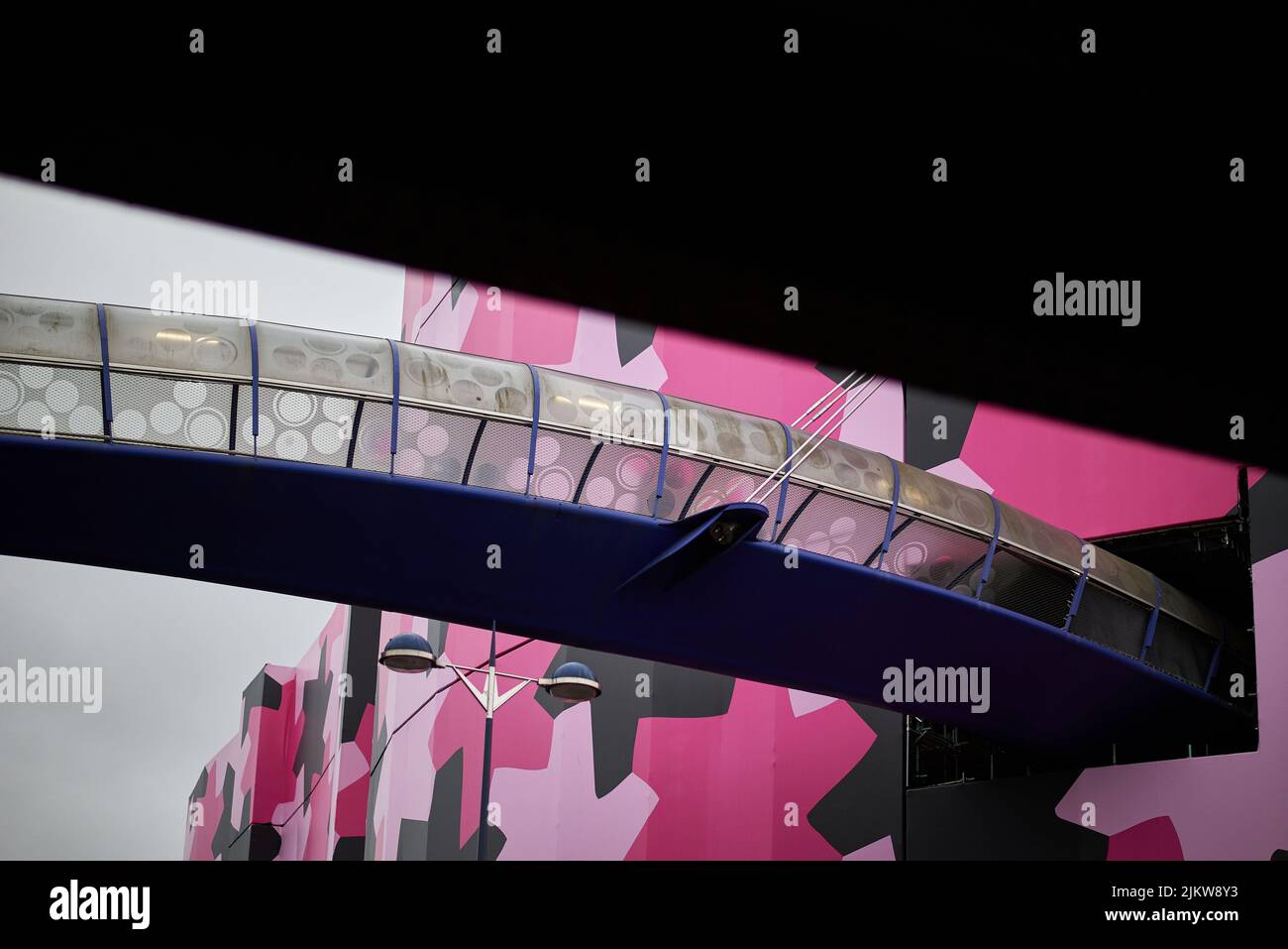 A low-angle shot of an enclosed footbridge connecting a car park to the ...