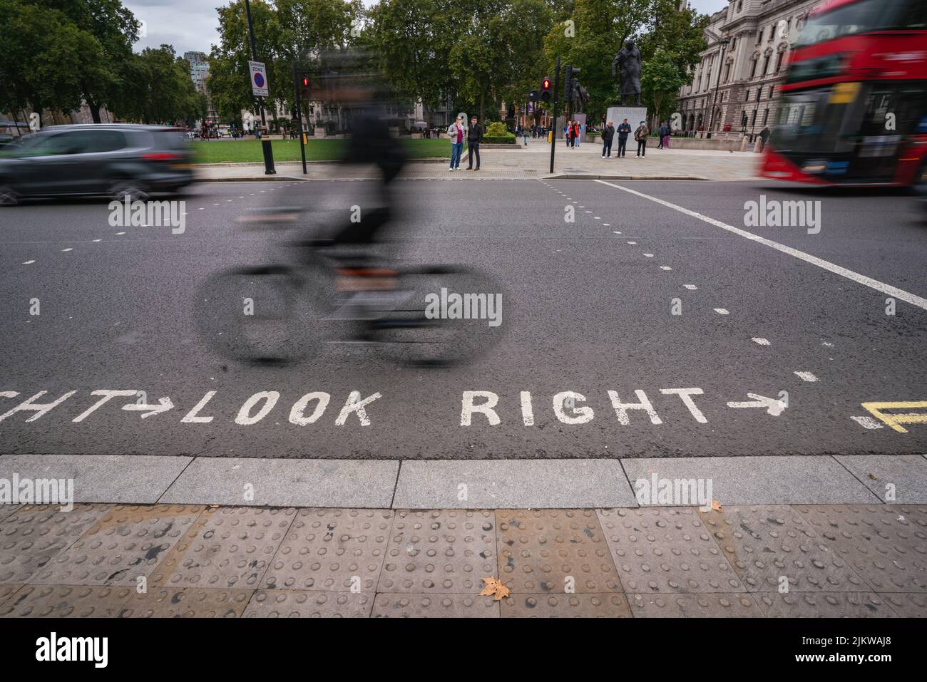 A road with a look right sign and a blurred bike rider Stock Photo - Alamy