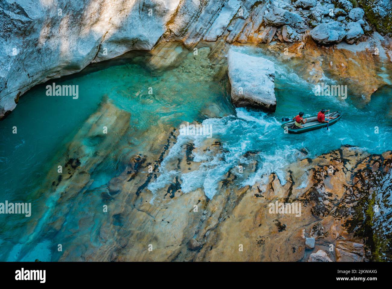 A beautiful shot of a people on a boat rafting on the rocky transparent ...